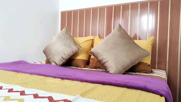 Uma cama com colcha estampada, duas almofadas e cabeceira.