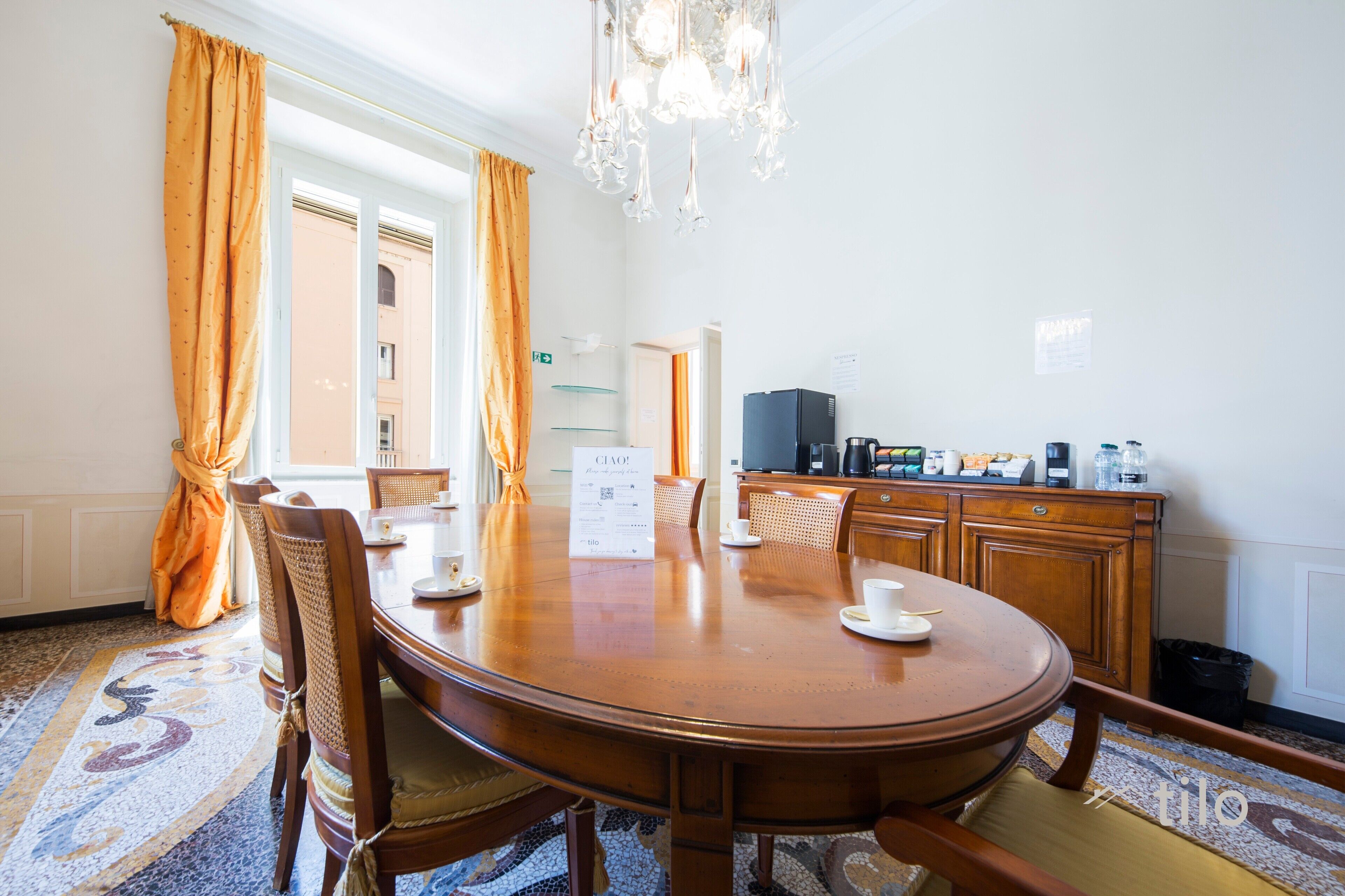 Uma sala de conferências com mesa de madeira, cadeiras, um candelabro e vista pela janela.