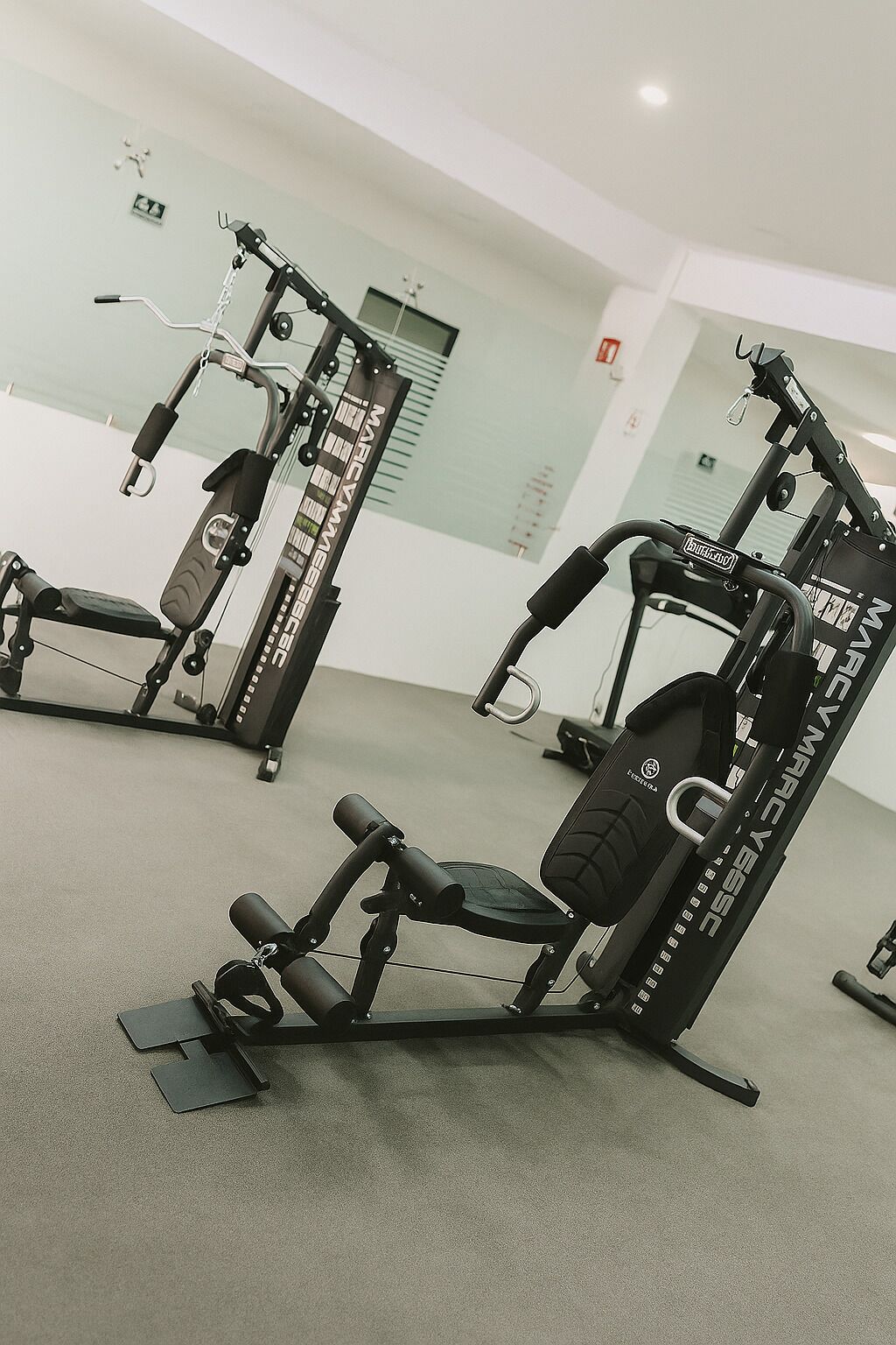 Uma academia com equipamentos de ginástica, incluindo um banco de musculação e uma estrutura para agachamentos.