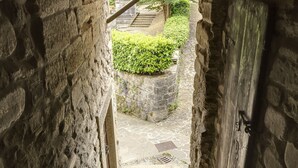 Escadaria de pedra que leva a uma área externa com vista para vegetação e um muro de pedra.