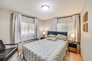 Quarto com uma cama, duas mesas de cabeceira, uma cadeira e cortinas.