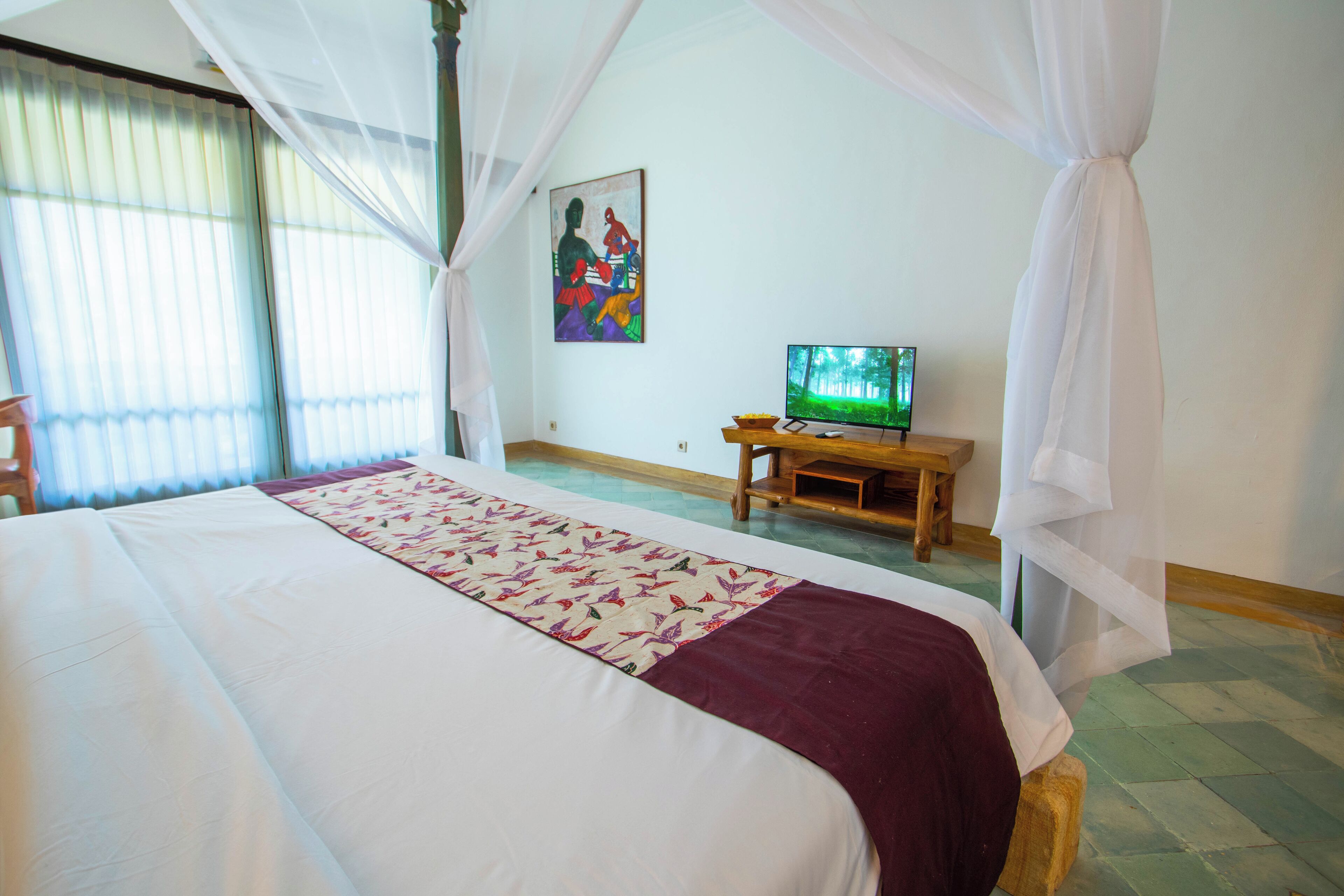 Quarto de hotel com uma cama grande, uma televisão e um quadro na parede.
