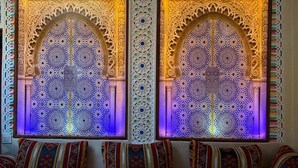 Quarto com janelas ricamente decoradas e um conjunto de almofadas coloridas com estampas listradas.