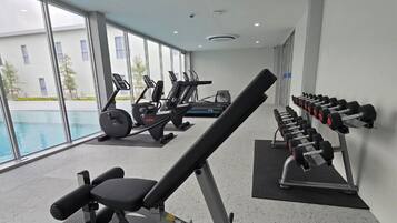 Uma academia com equipamentos de exercícios, aparelho de supino e halteres.