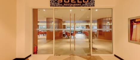 Entrada do Restaurante Suele, com interior moderno visível através das portas de vidro.