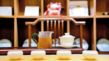 Um conjunto de chá tradicional sobre uma mesa de madeira, com bule, xícara e pires, e um jarro de chá.