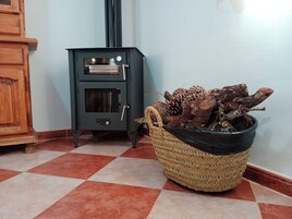 Um quarto com uma lareira a lenha de madeira escura, uma cesta de madeira com lenha e um armário de madeira.