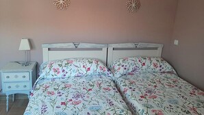 Quarto com duas camas, mesa de cabeceira e arte decorativa na parede.