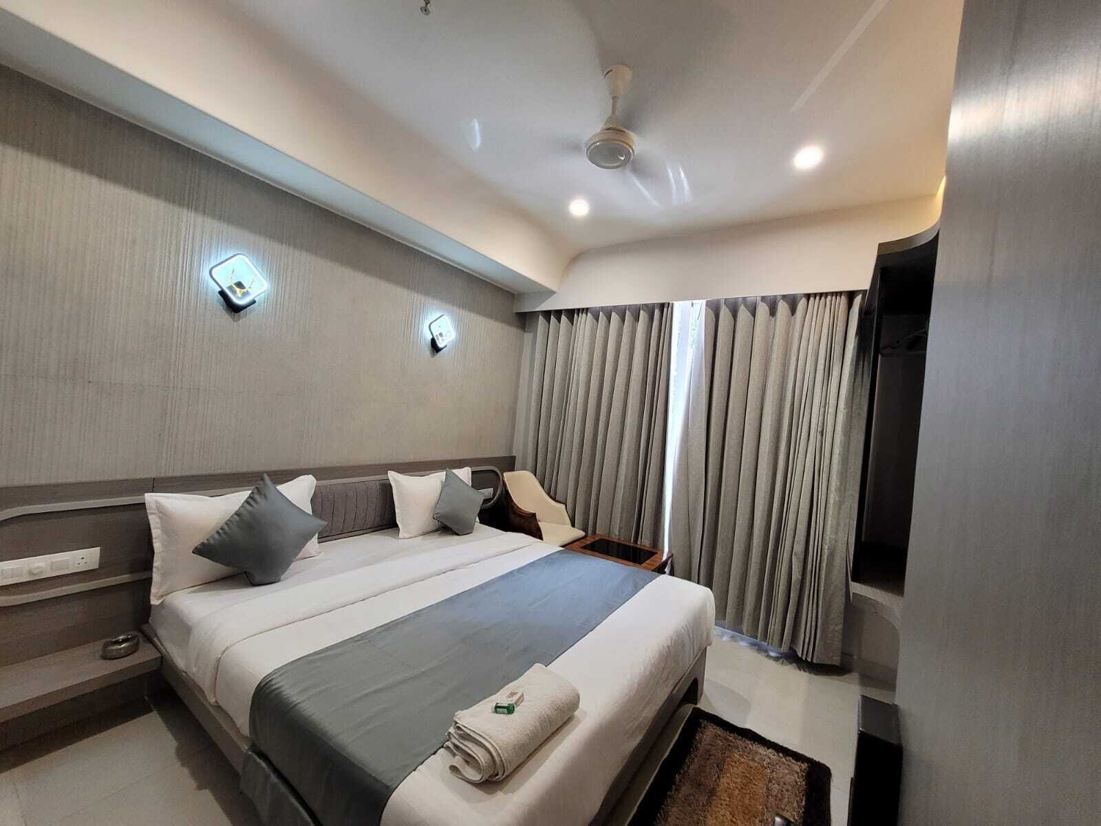 Quarto de hotel moderno com uma cama grande, televisão de tela plana e ventilador de teto.