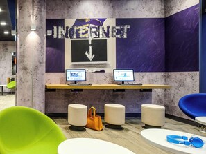 Um espaço de trabalho moderno com dois computadores numa estante, uma cadeira verde e uma cadeira azul.