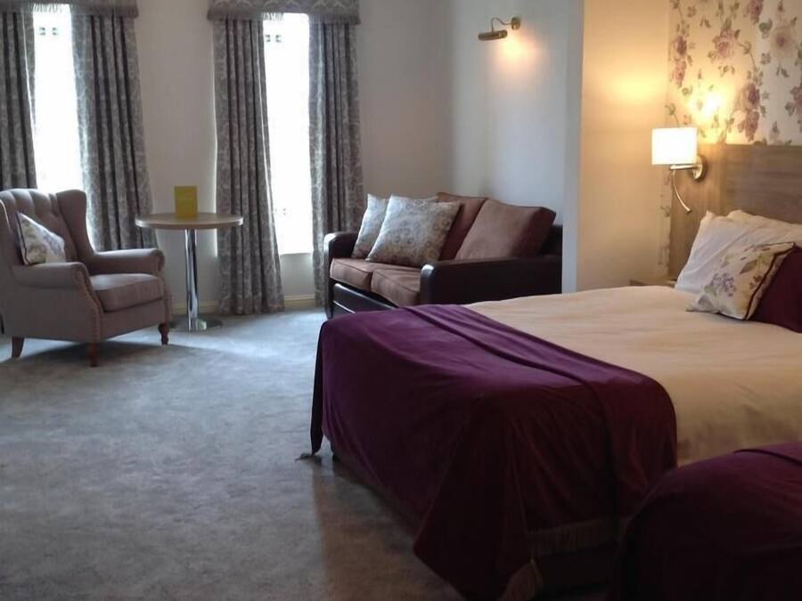Quarto de hotel com uma cama grande, um sofá, uma cadeira e uma pequena mesa.