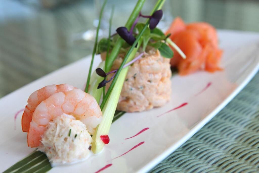 Um prato de sushi com camarão, cobertura cremosa e guarnições.