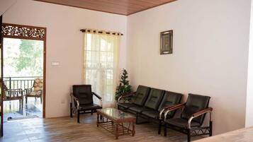 Uma sala de estar com sofá, duas poltronas, uma mesa de centro e um pequeno pinheiro de Natal.