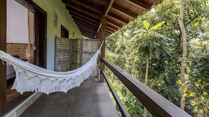 Uma rede numa varanda com vista para vegetação densa.