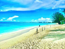 Perto da praia, areia branca, espreguiçadeiras, guarda-sóis 