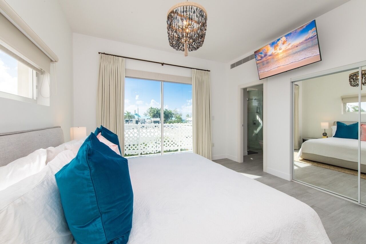 Quarto de hotel com uma cama grande, um candelabro, uma TV e uma varanda com vista.