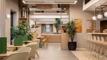 Um espaço de escritório moderno com área de recepção, diversas opções de assentos e vários vasos de plantas.
