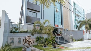 Um edifício moderno com fachada de vidro, entrada visível e uma placa com o nome