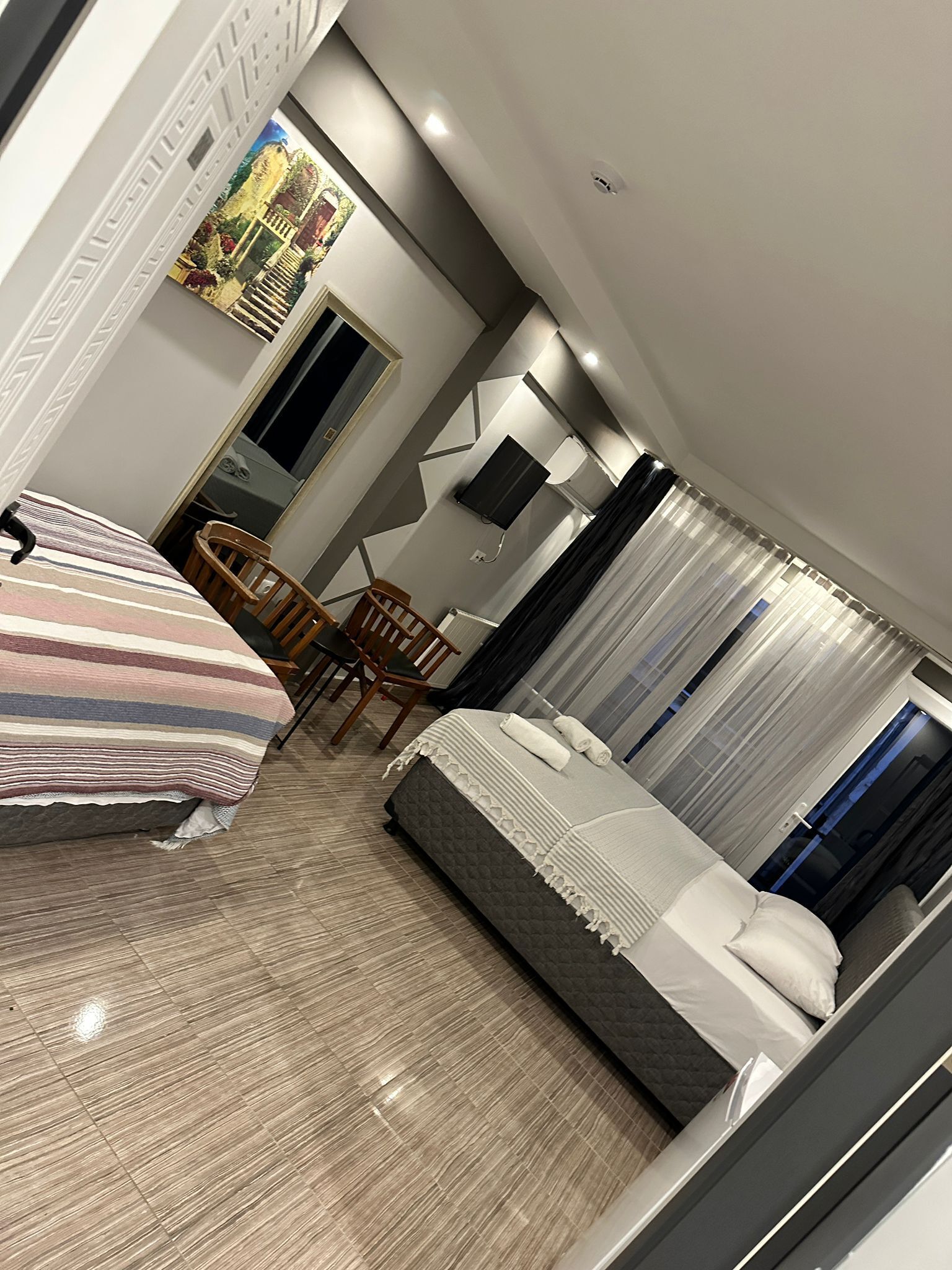Quarto de hotel compacto com duas camas, um pequeno espaço para sentar e um quadro na parede.