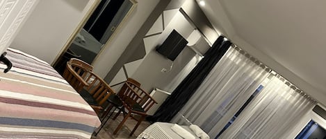 Quarto de hotel compacto com duas camas, um pequeno espaço para sentar e um quadro na parede.