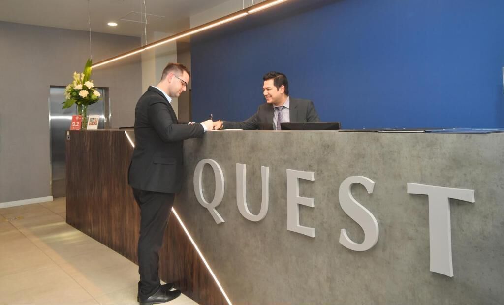 Um balcão de recepção com a palavra "QUEST" em destaque.
