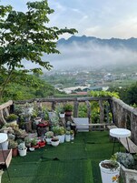 Jardim no terraço com diversos vasos de plantas e um banco de madeira.