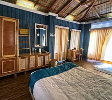 Um quarto com cama, móveis de madeira, um espelho e uma janela com cortinas.
