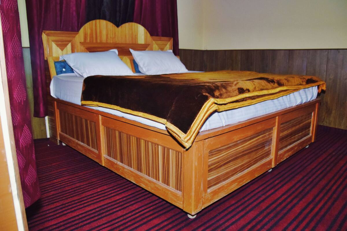 Uma cama de madeira com cabeceira, um tapete vermelho e um cobertor marrom.