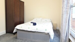 Quarto com cama, guarda-roupa e janela com cortinas.