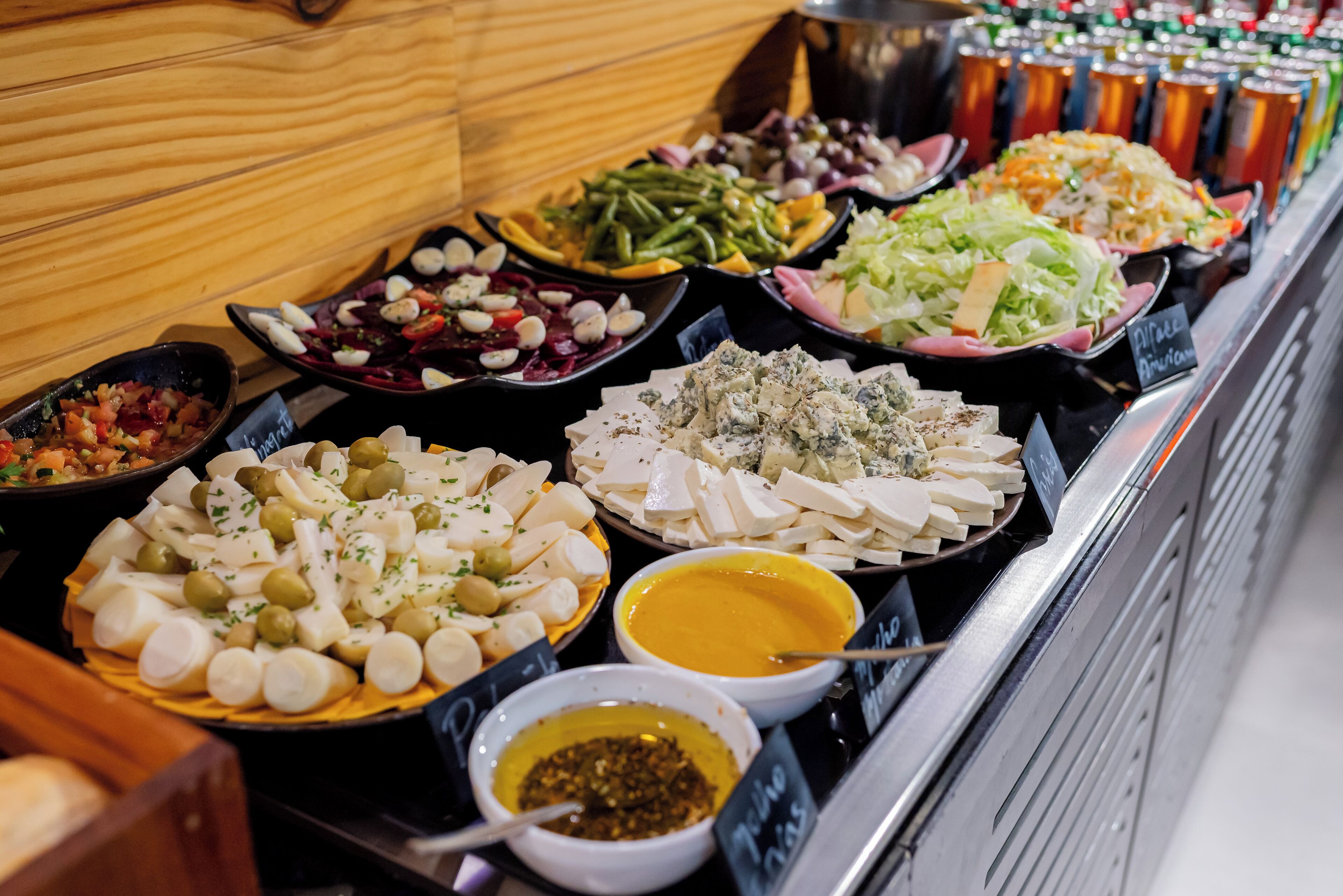 Buffet com diversos pratos, incluindo queijos, saladas e patês.