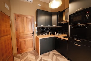 Cozinha moderna com armários de madeira, forno preto e piso em padrão herringbone.