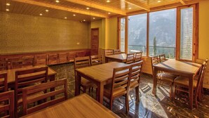 Restaurante com interiores em madeira, piso de mármore e grandes janelas com vista para as montanhas.