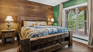 Quarto rústico com estrutura de cama de madeira, duas mesas de cabeceira com abajures e uma janela grande com cortinas.