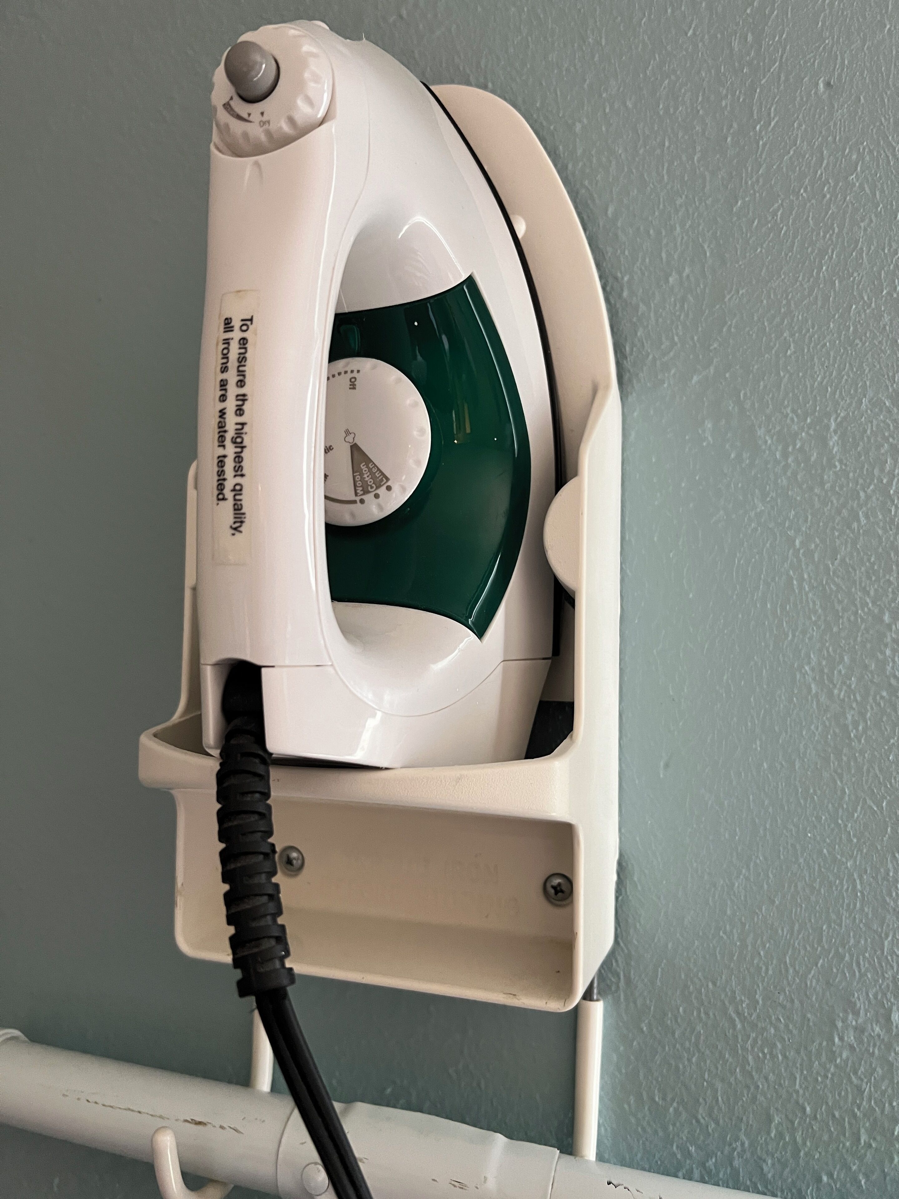 Um secador de cabelo branco com um bico verde, fixado na parede.