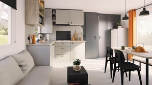 Uma cozinha moderna com armários brancos, uma área de refeições com mesa e cadeiras, e um sofá.