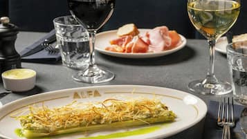 Uma mesa de jantar com um prato de comida, duas taças de vinho e um moedor de pimenta.