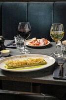 Uma mesa de jantar com um prato de comida, duas taças de vinho e um moedor de pimenta.