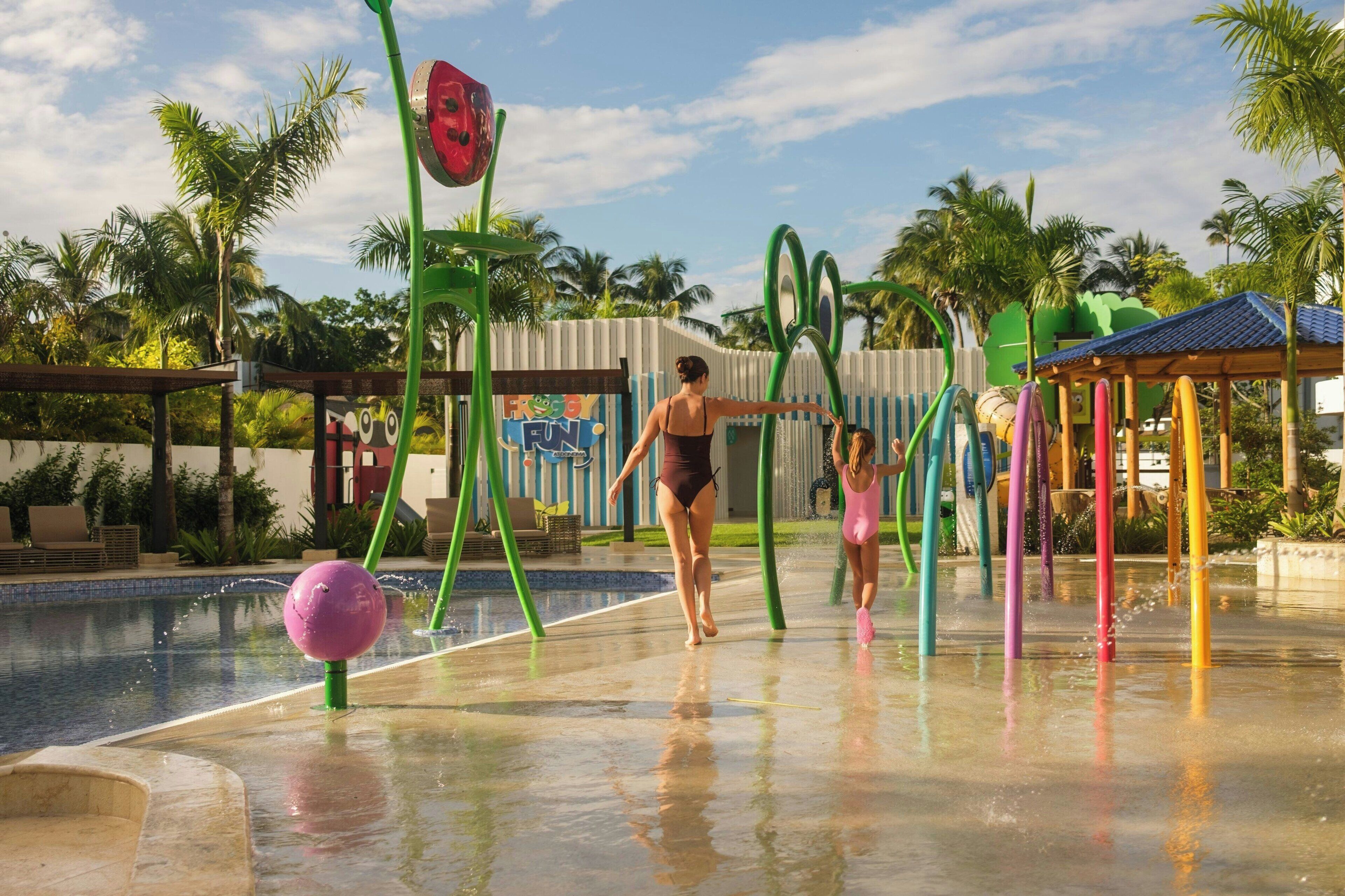 Um parque aquático com piscina, toboáguas coloridos e palmeiras.