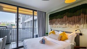 Quarto de hotel moderno com uma cama grande, varanda com vista para a cidade e parede com textura única.
