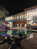 Um hotel moderno com piscina, área externa para sentar e escadaria que leva a um andar superior.