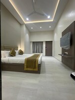 Quarto de hotel moderno com cama grande, ventilador de teto, iluminação embutida, televisão de tela plana e porta que dá para uma varanda.