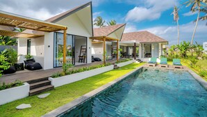 Uma área moderna com piscina ao ar livre, vista clara da piscina, espreguiçadeiras e um espaço de estar coberto.