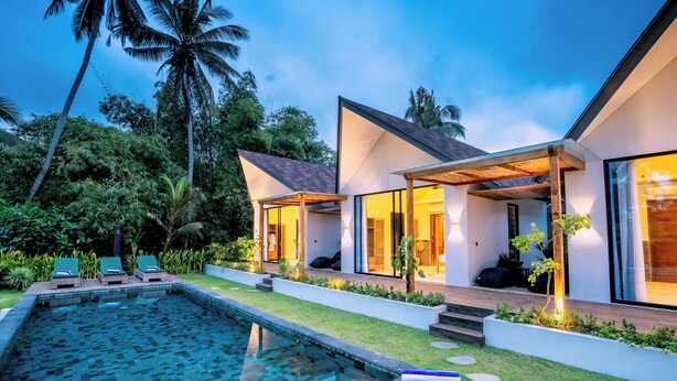 Uma casa moderna com piscina, área de estar externa e vegetação exuberante.