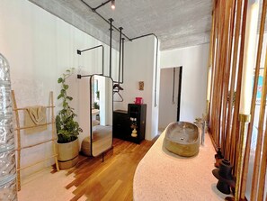 Um interior moderno com piso de madeira, um espelho, uma planta e um armário preto.