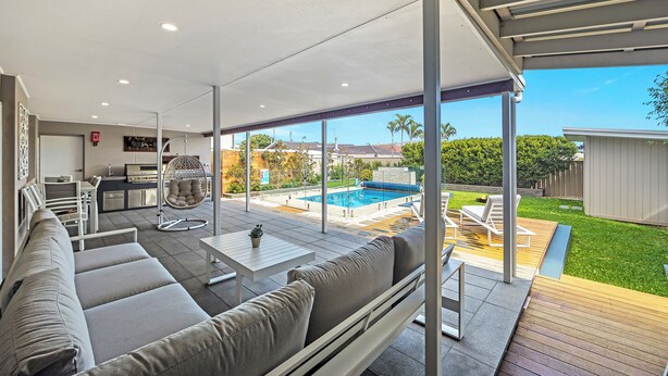 Uma área externa moderna com piscina, um sofá e uma mesa de jantar.