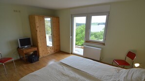 Quarto com cama, televisão, guarda-roupa e janela com vista.