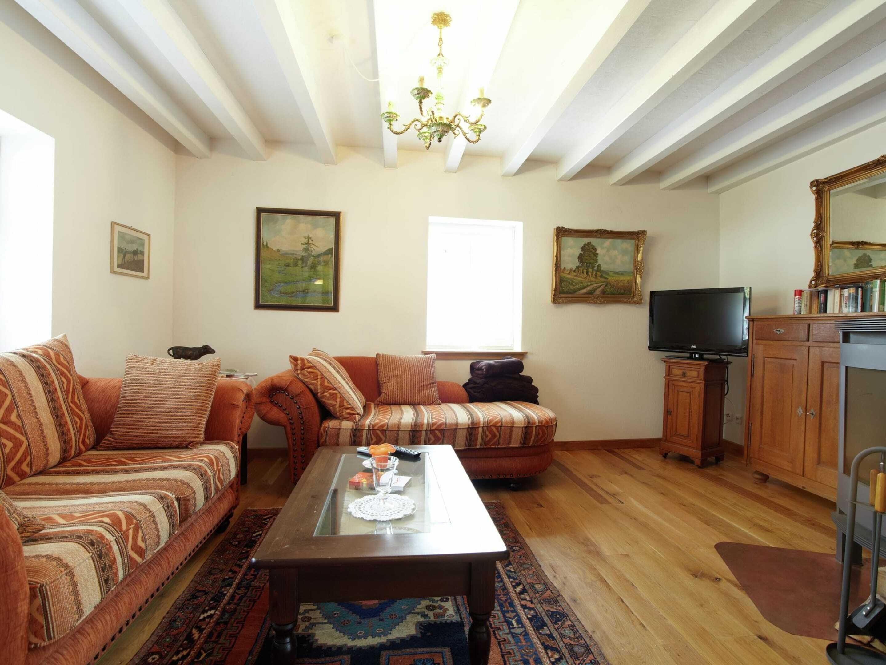 Uma sala de estar com dois sofás, uma mesa de centro, uma televisão e um armário.