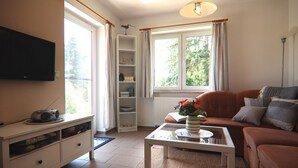 Uma sala de estar com televisão, sofá, mesa de centro e estante de livros.