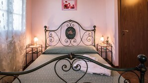 Quarto com cama, duas mesas de cabeceira, porta de madeira e quadro pendurado na parede.