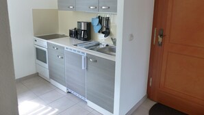 Uma cozinha compacta com forno embutido, cafeteira e pia.